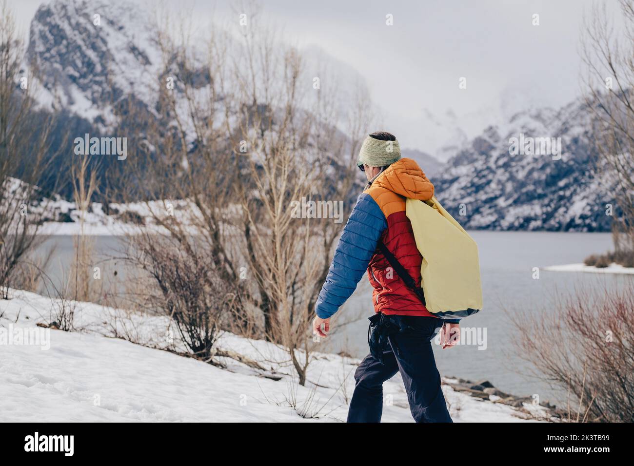 Side view of tourist with knapsack walking on stone in snow and ...
