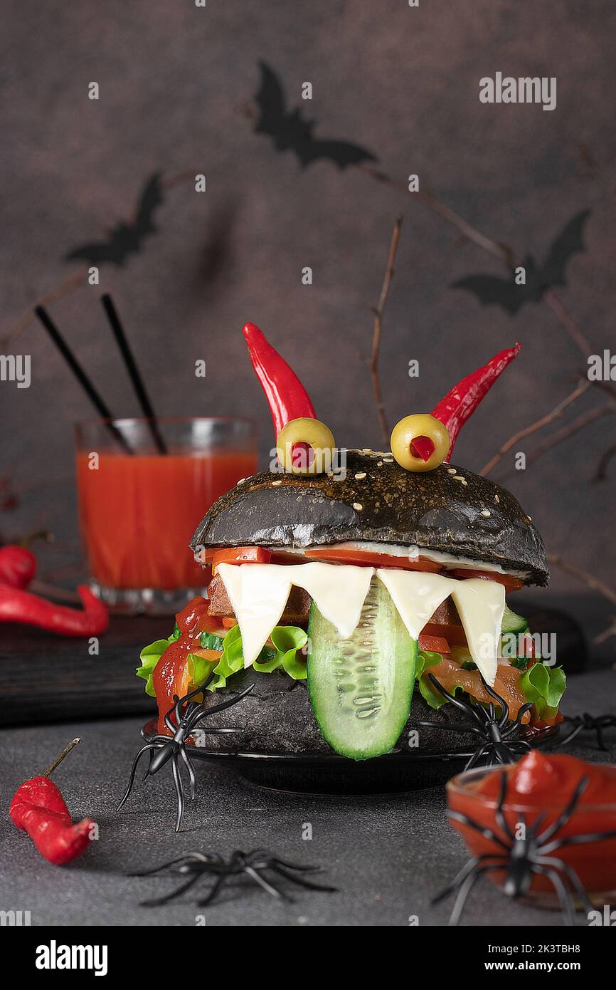 Funny monster black burger with fish, toast cheese, cucumber, tomato ...