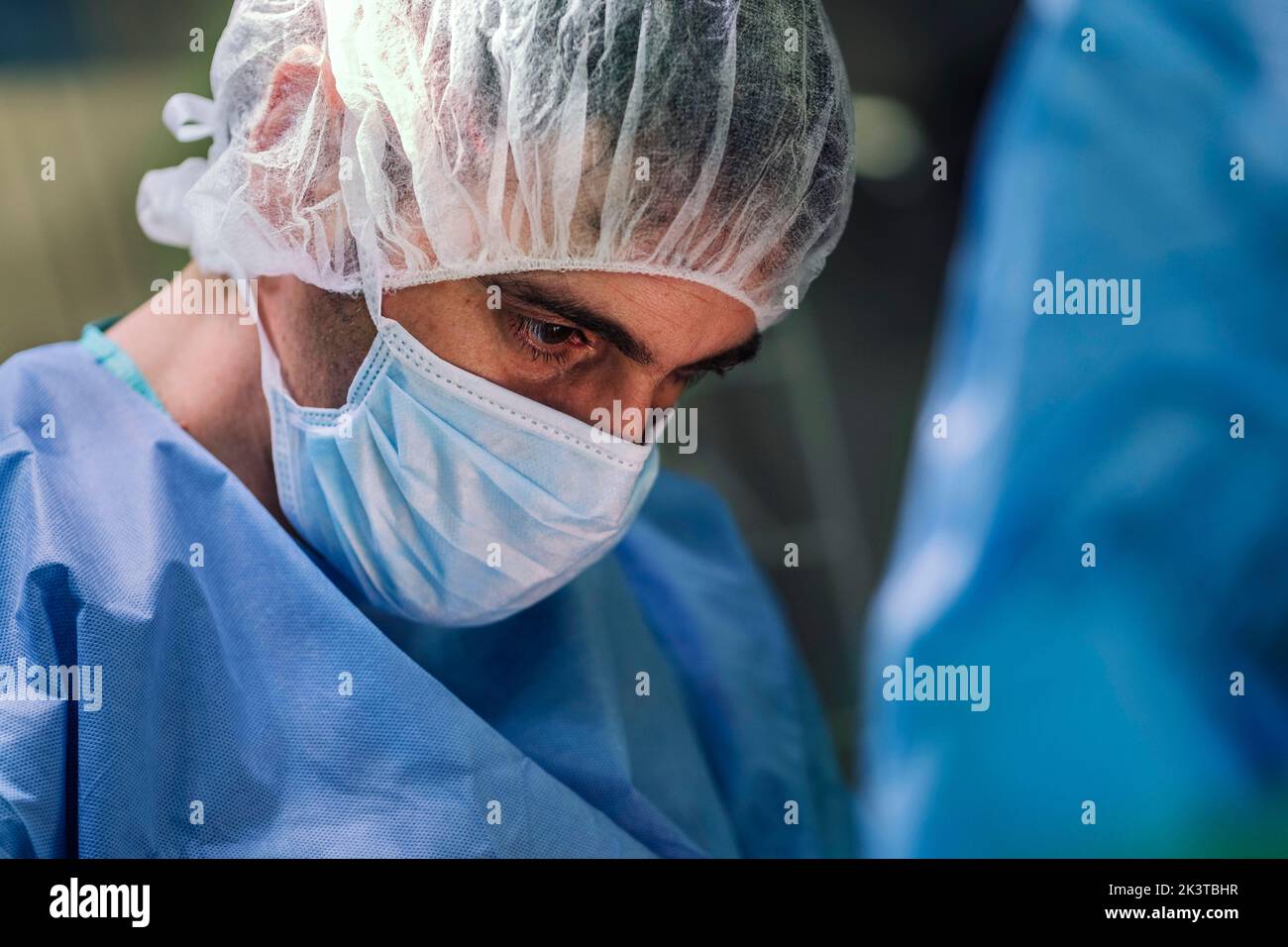 Crop side view of serious and concentrated male doctor working in light ...