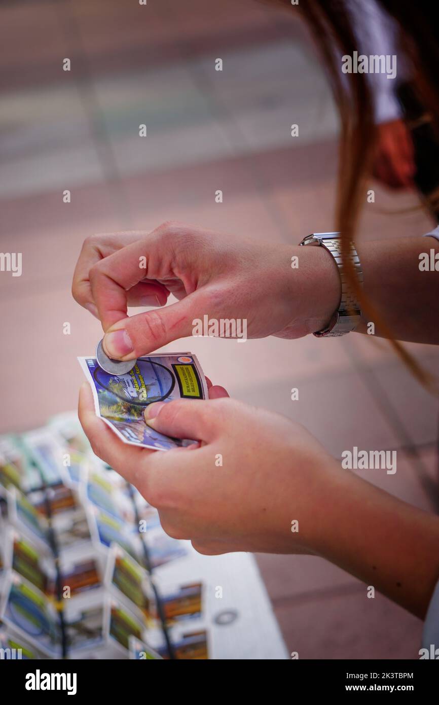 A closeup of the hands playing a scratch game Stock Photo - Alamy