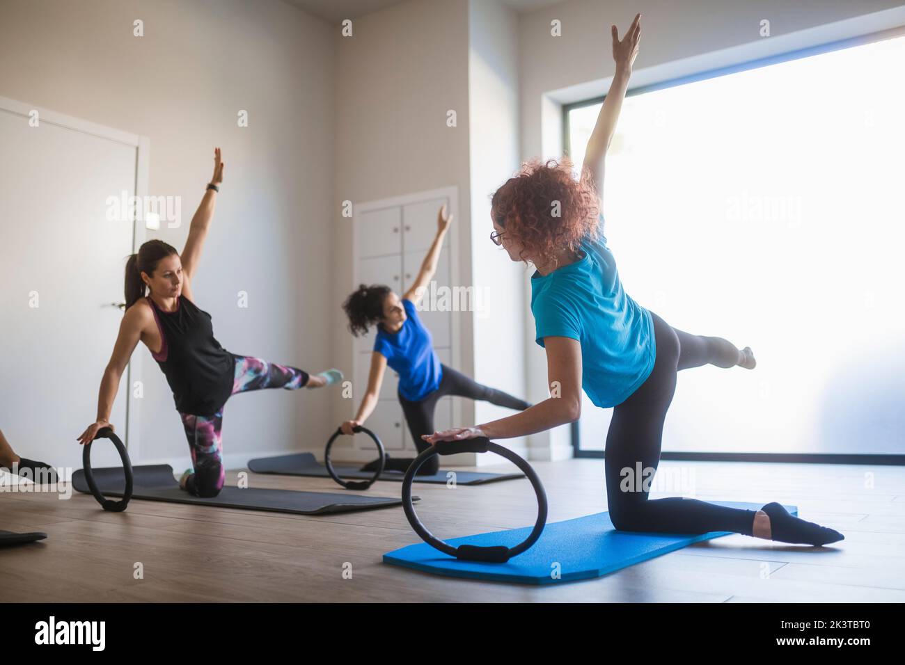 Female trainer with group of women doing exercise with pilates ring ...
