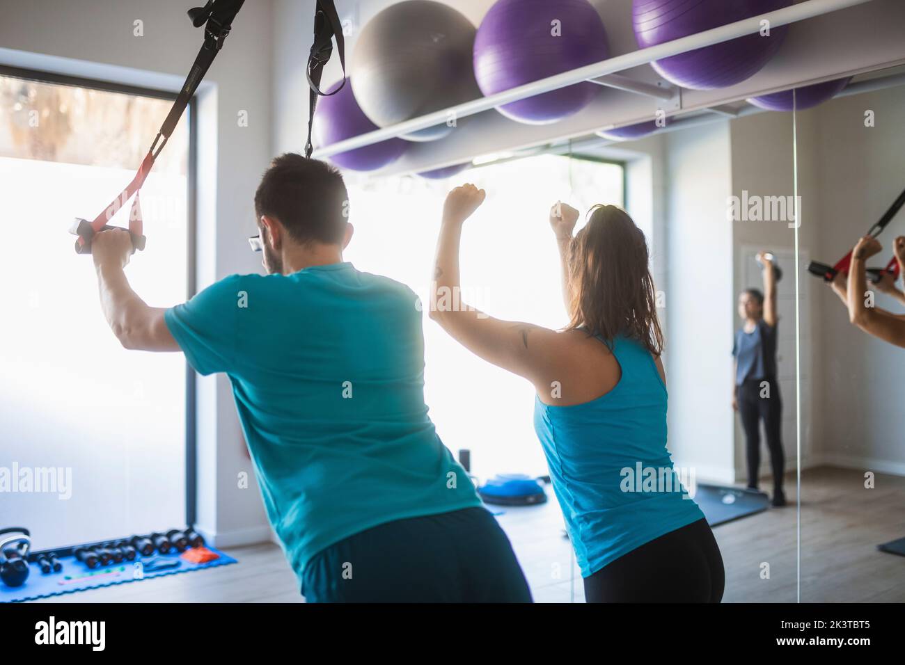 Back view of female instructor demonstrating technique of exercise with ...