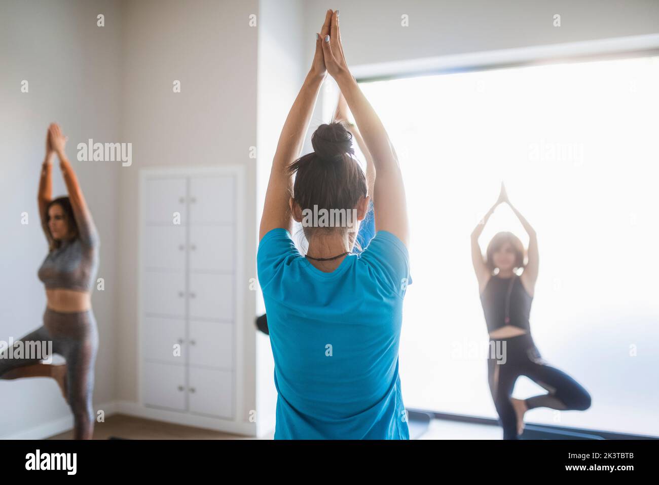 Back view of unrecognizable female instructor demonstrating Tree pose ...