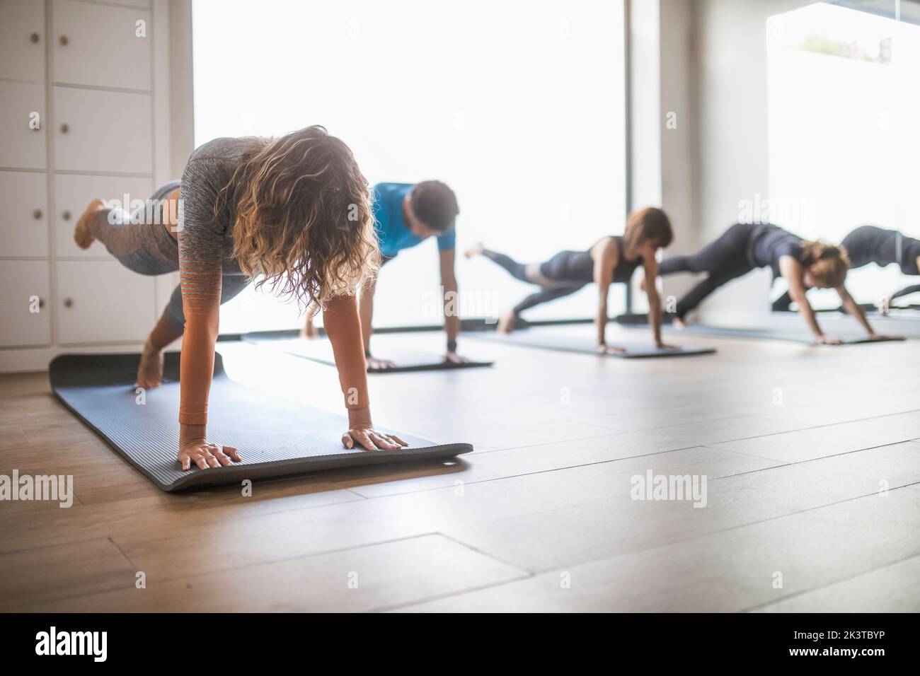 Unrecognizable female doing balancing One Legged Plank asana on mat ...