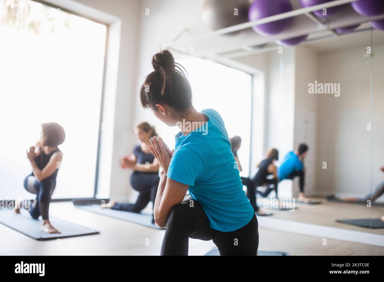 Side view of flexible female yoga trainer doing Revolved Crescent Lunge ...