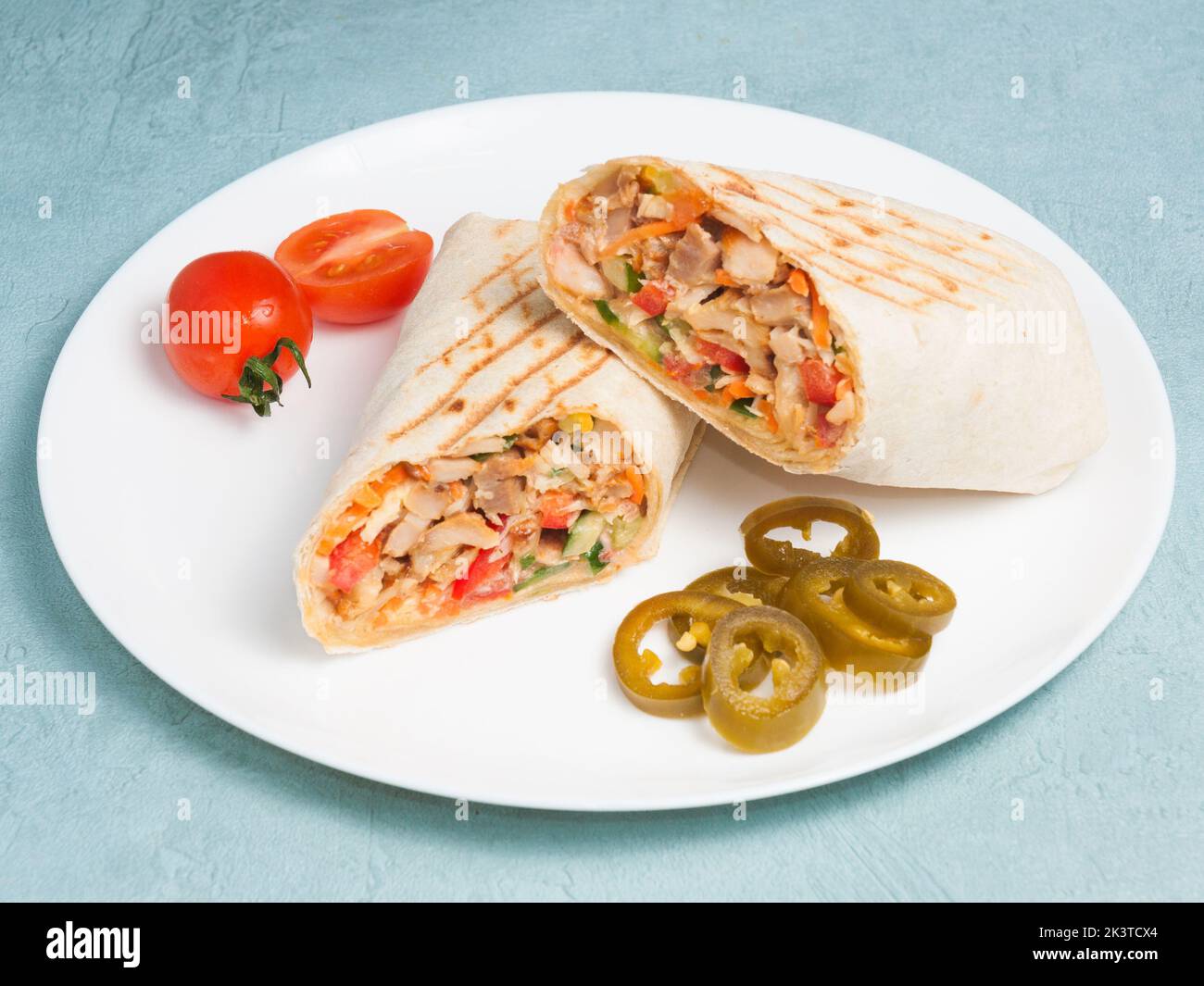 tasty shawarma with chicken and vegetables, jalapeno pepper on a blue ...
