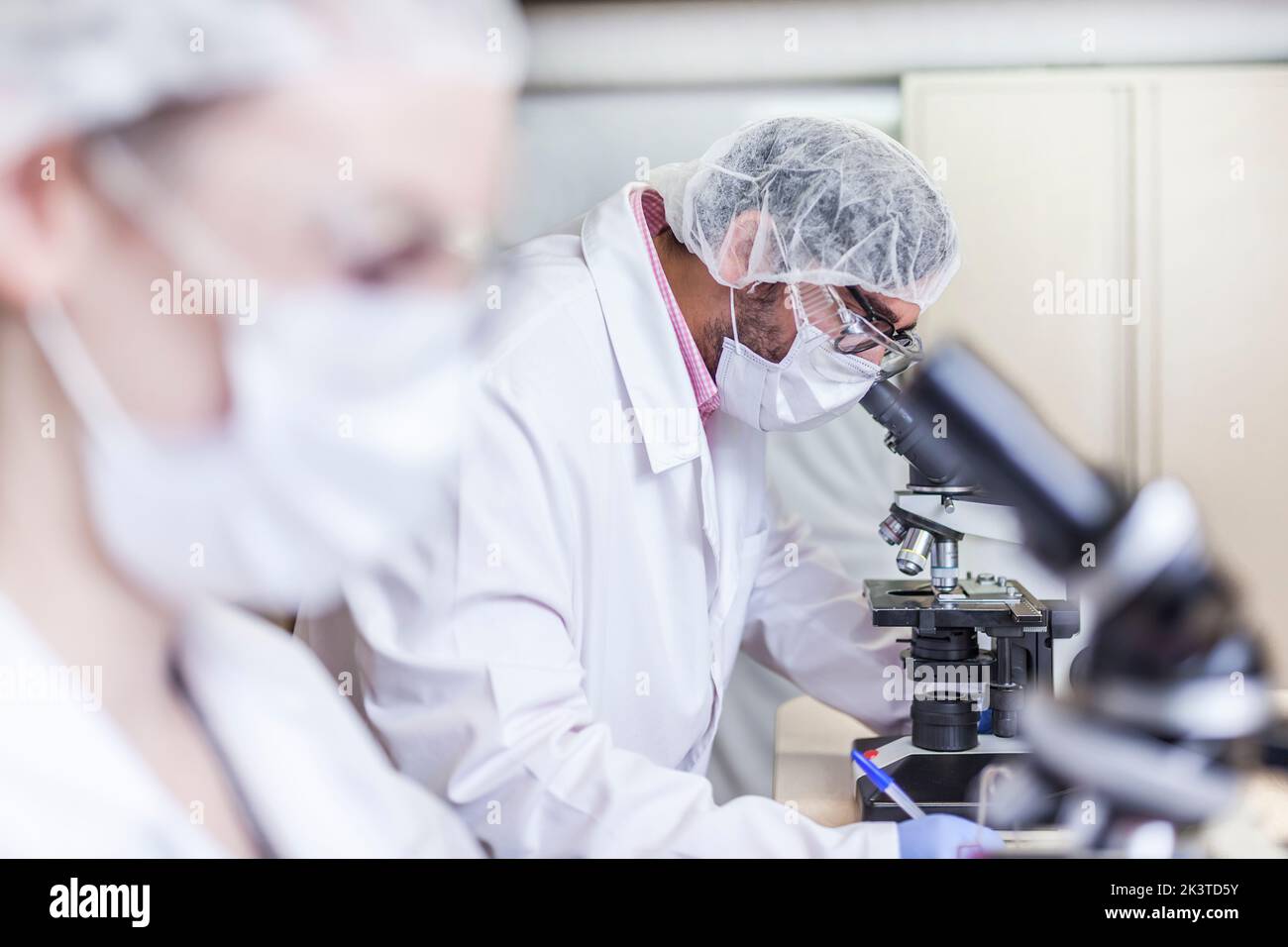 man and woman scientists looking through microscope at laboratory Stock ...