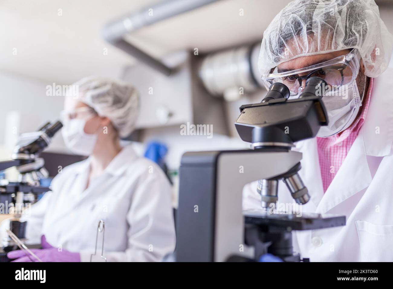 man and woman scientists looking through microscope at laboratory Stock ...