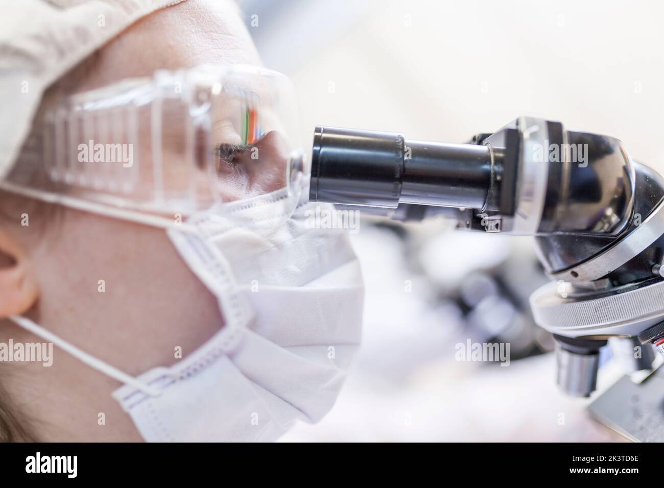close-up side view of woman scientist looking through microscope at ...