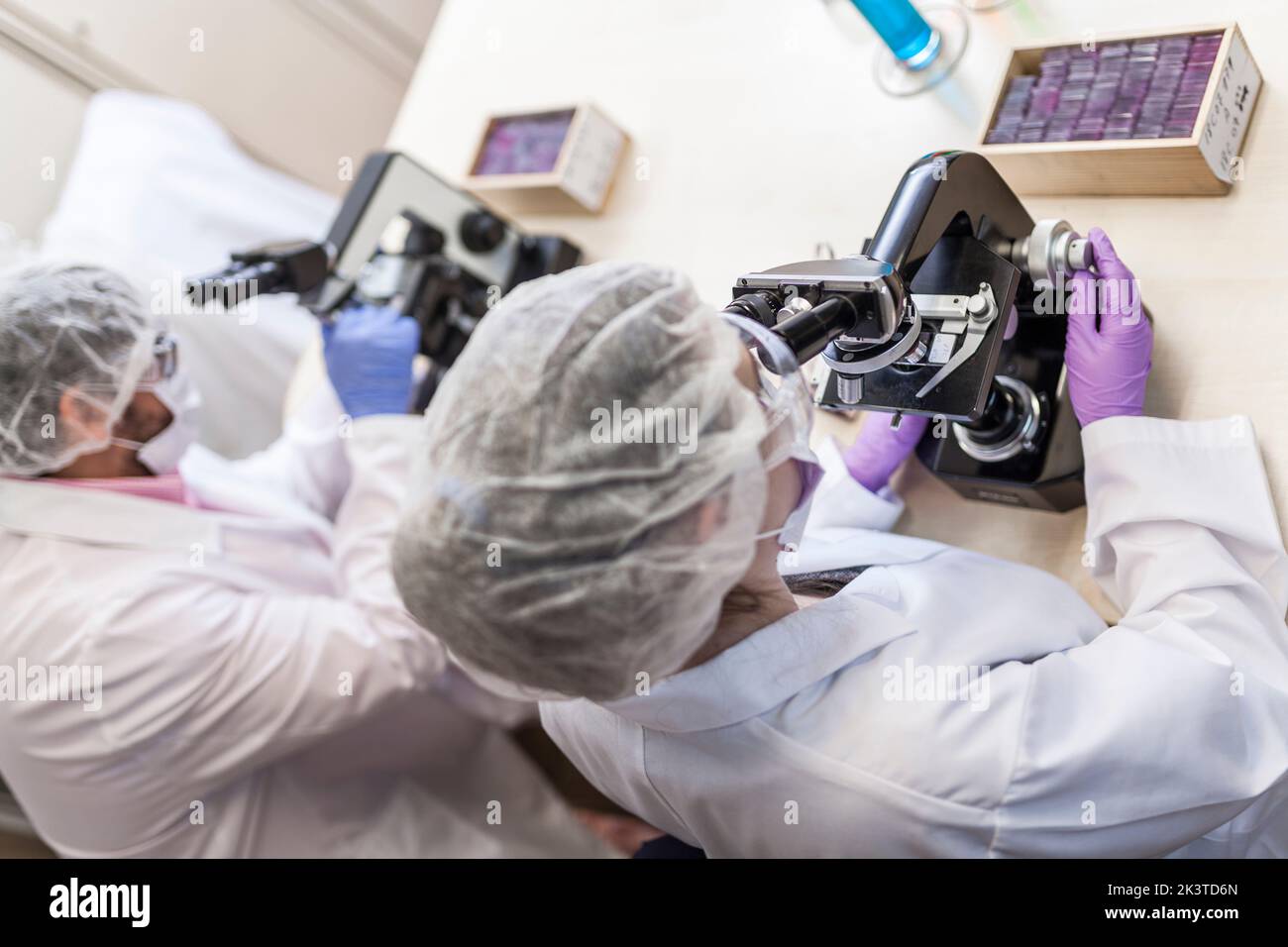 From above woman scientist looking through microscope at laboratory ...