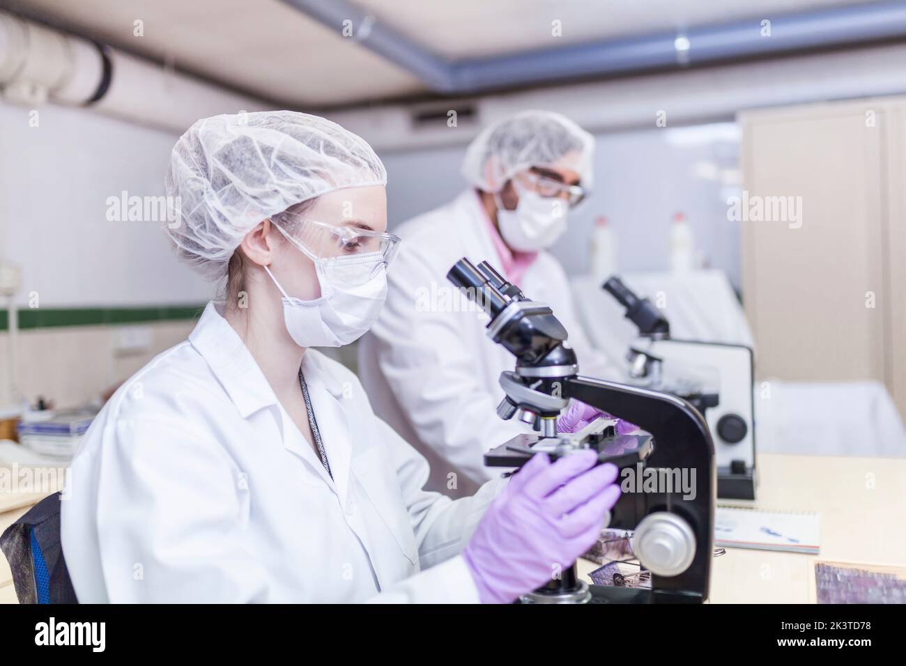 man and woman scientists looking through microscope at laboratory Stock ...