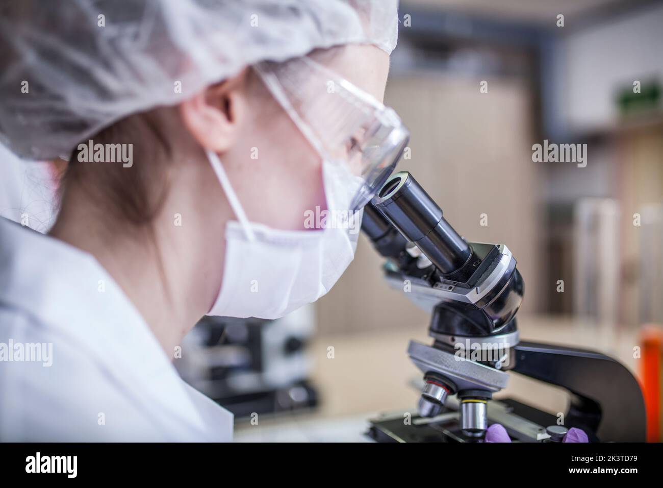 close-up side view of anonymous woman scientist looking through ...