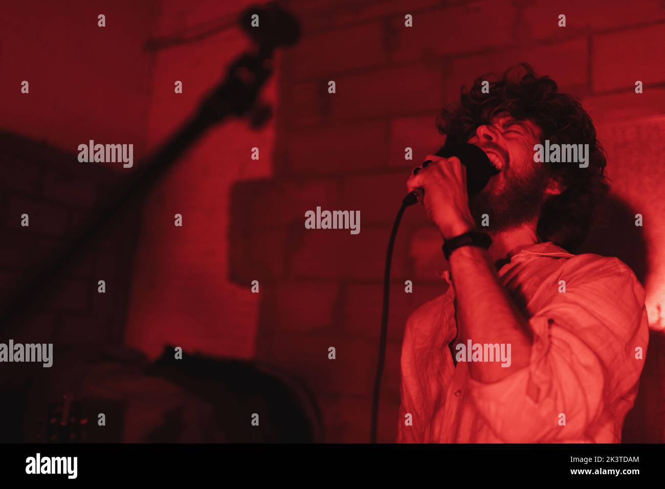 Trendy man singing with a rock band in red light at studio Stock Photo ...