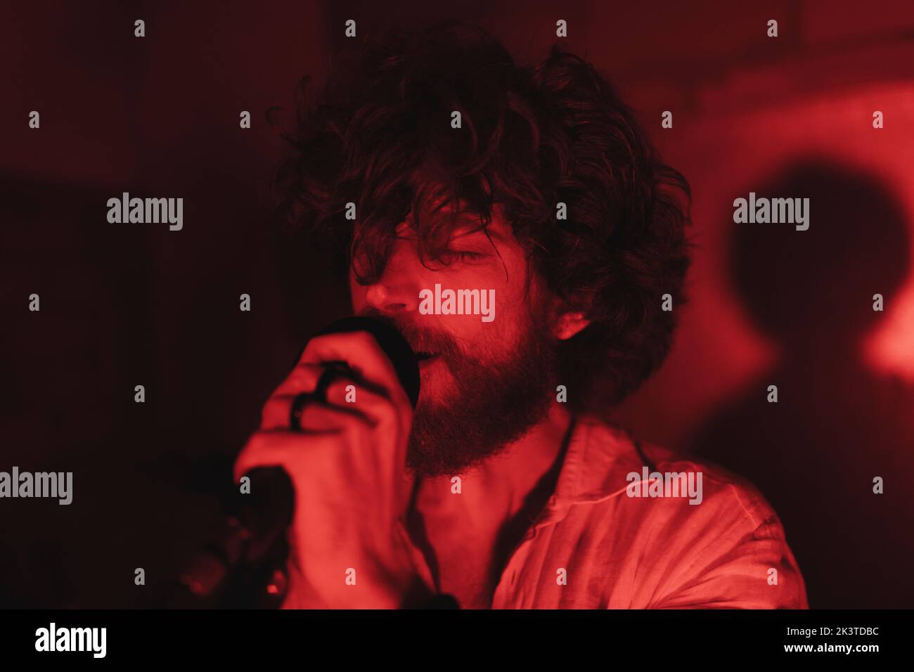 Trendy man singing with a rock band in red light at studio Stock Photo ...