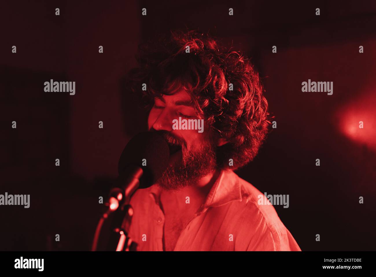 Trendy man singing with a rock band in red light at studio Stock Photo ...