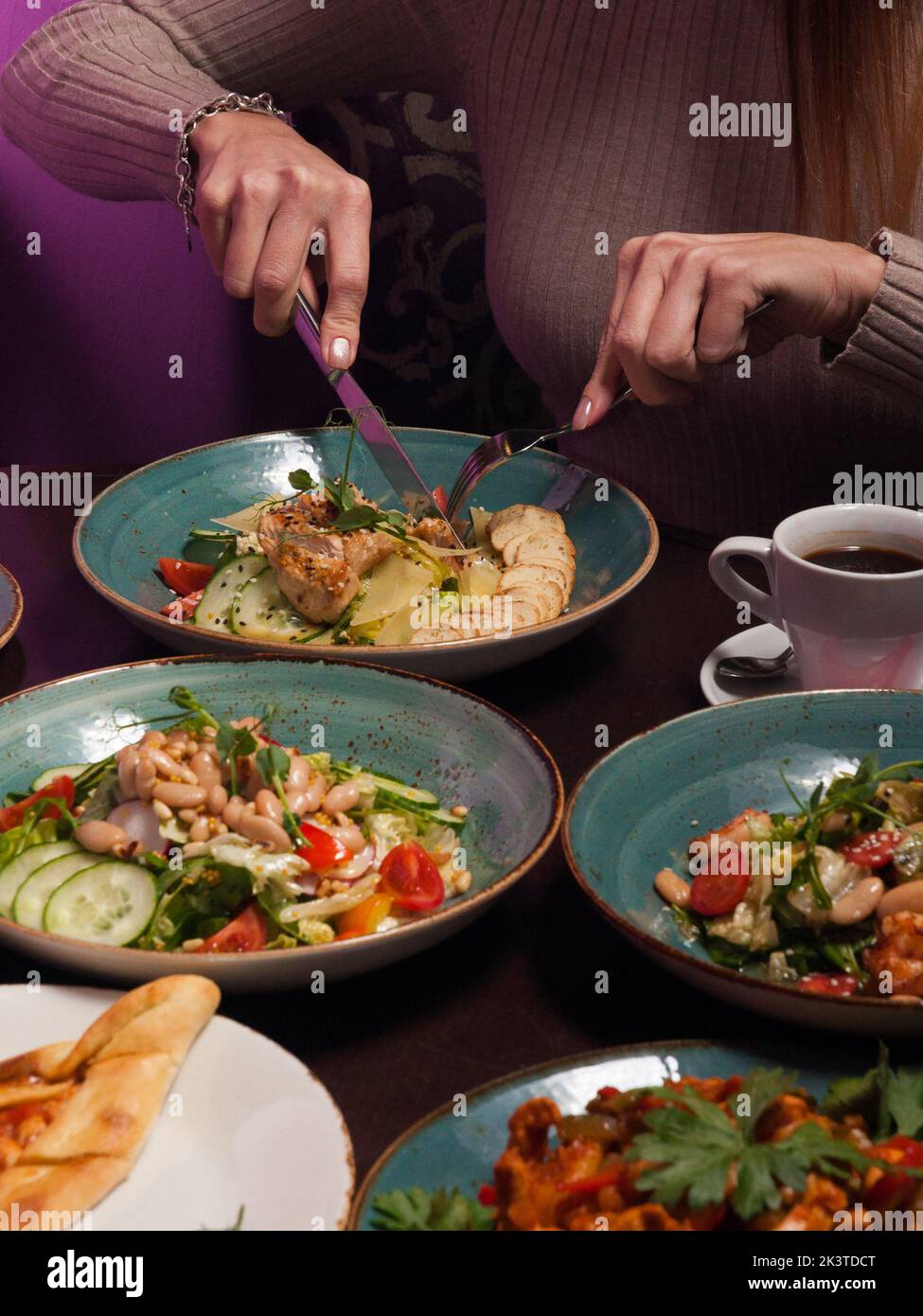 a girl eats in a restaurant. a full table of food. concept: abundance ...