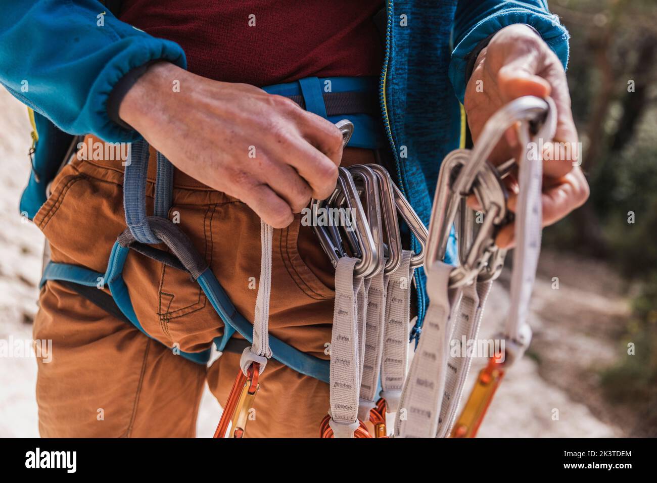 Hands of a climber preparing insurance rope and carabiners to climb ...