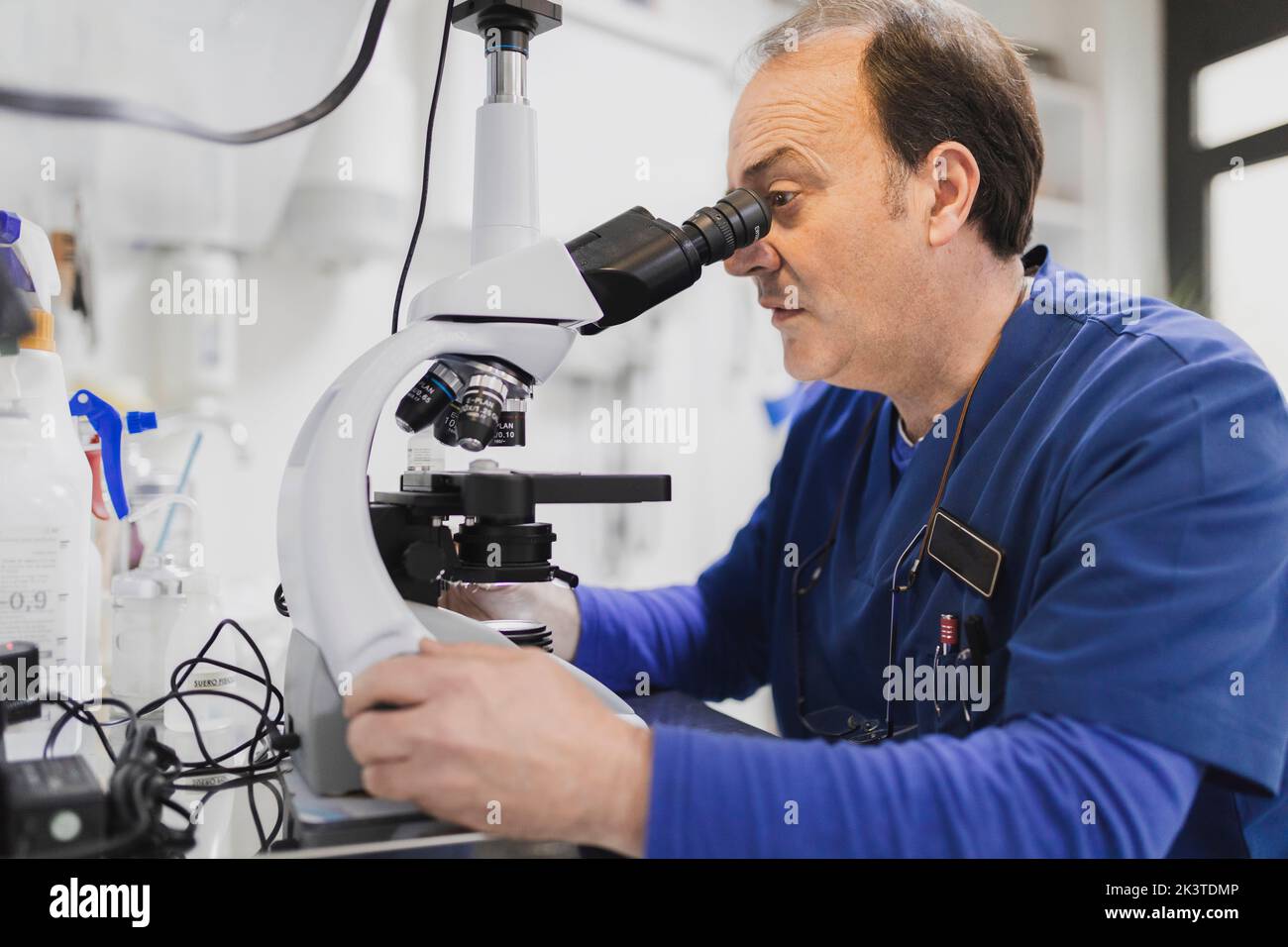 Doctor looking through microscope in hi-res stock photography and ...