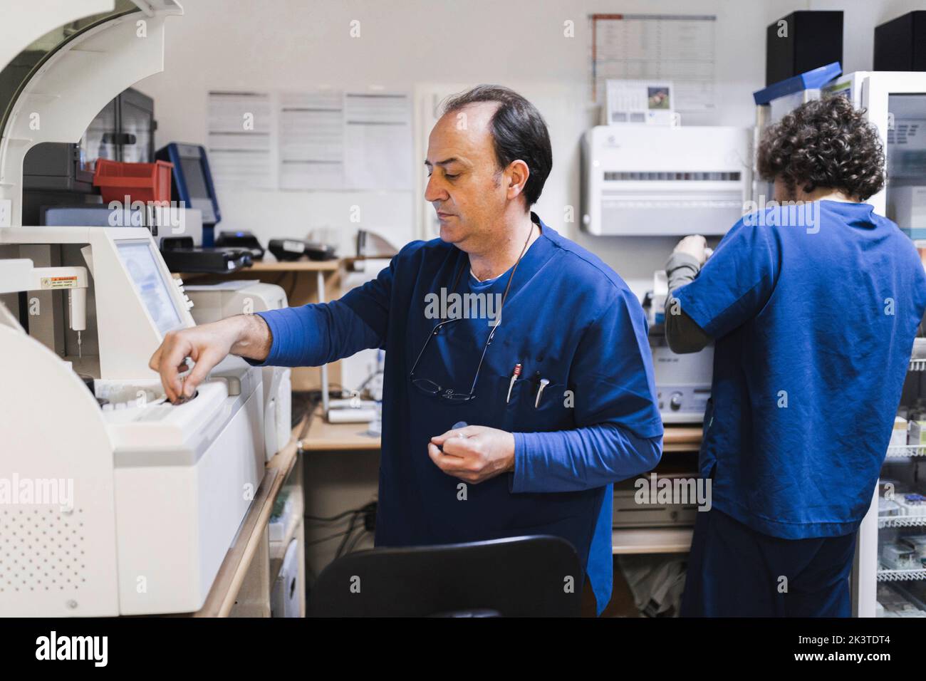 Side view of male doctors in uniform working near chemistry test ...