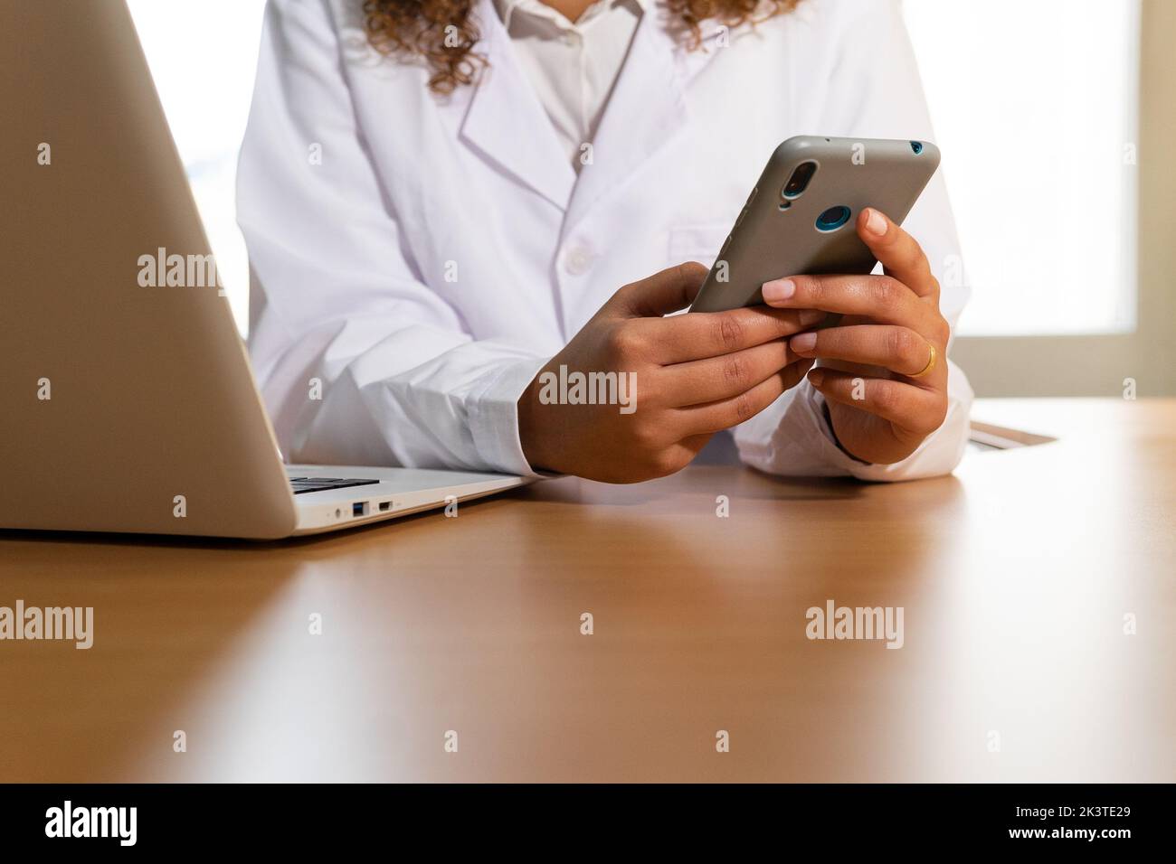 Anonymous crop adult ethnic female doctor in uniform text messaging on ...