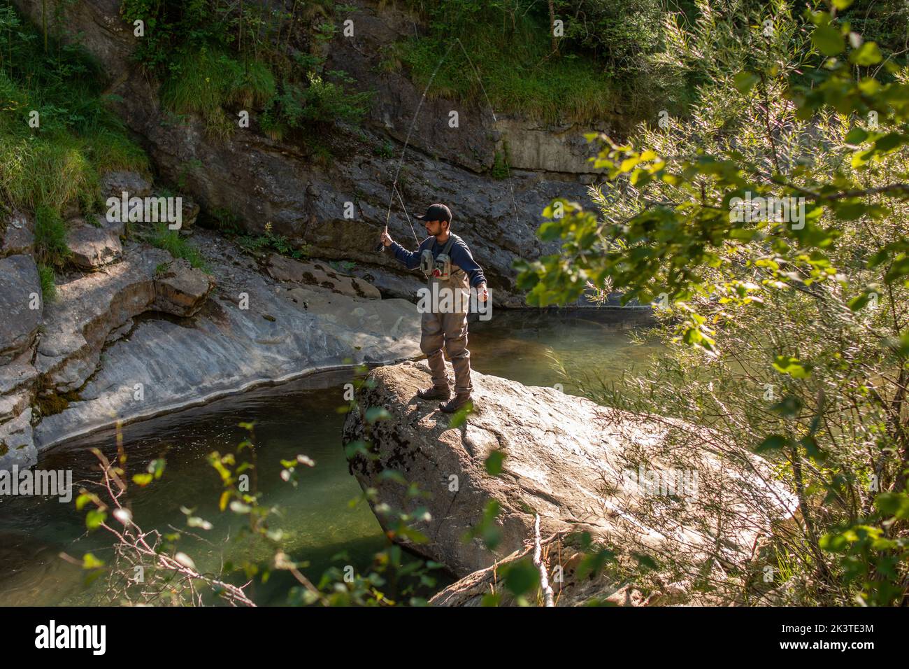 From above male fisherman throwing fishing rod into a mountain river ...