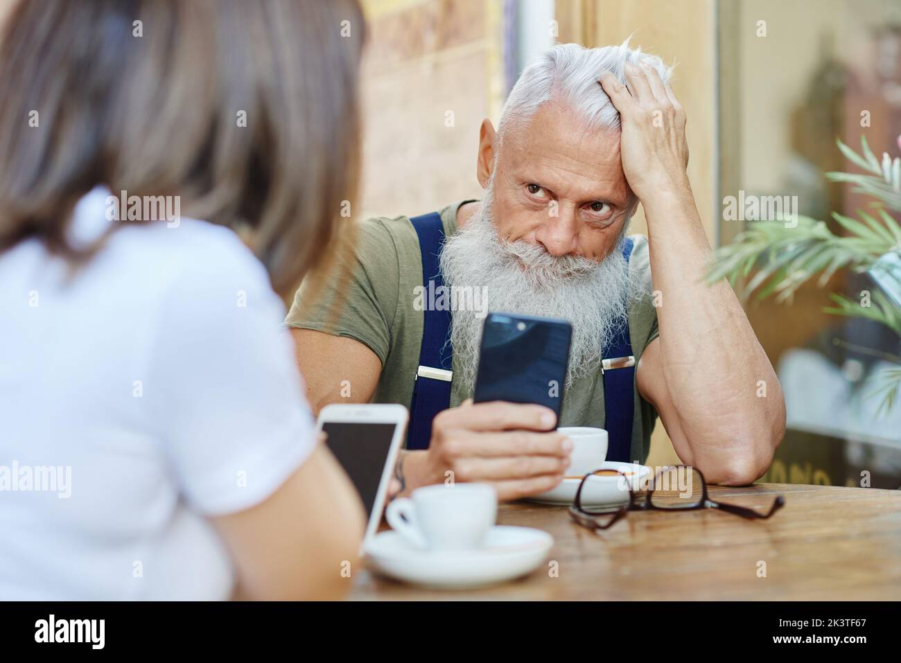 Stylish worried dandy grandpa browsing on smartphone touching head in ...