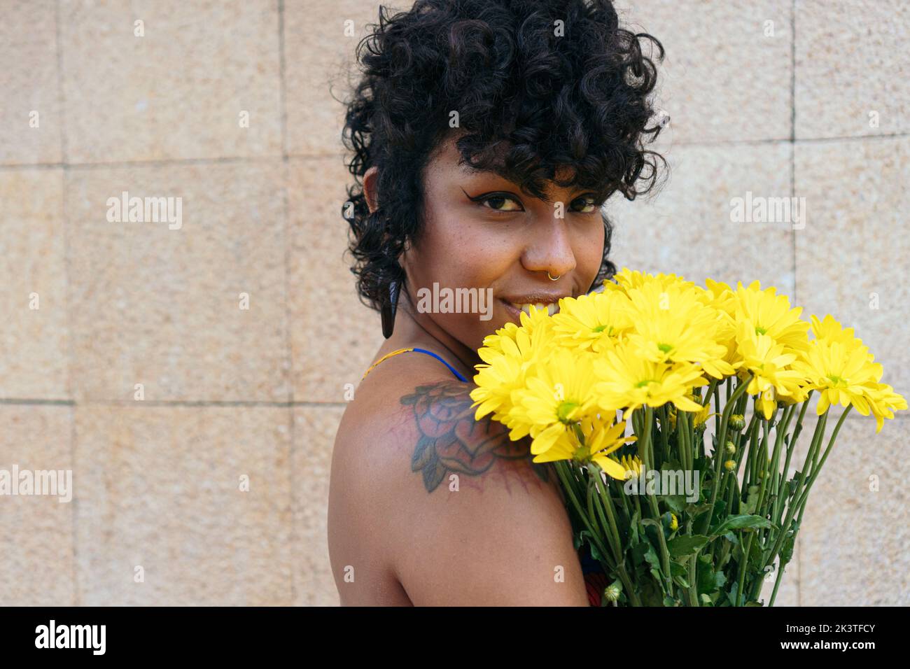 Tender ethnic female in summer clothes standing with bunch of bright ...