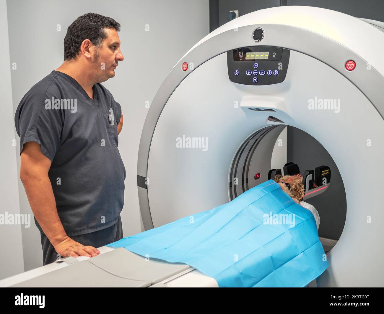Side view of adult man operating MRI scanner during pet examination in ...