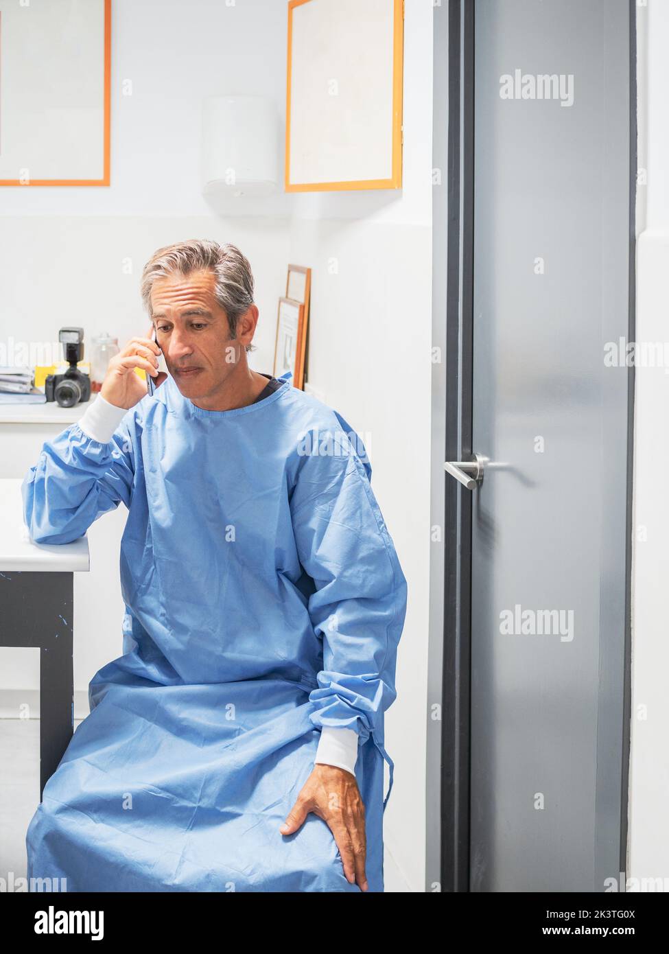 Mature man in medical uniform answering phone call while working in ...