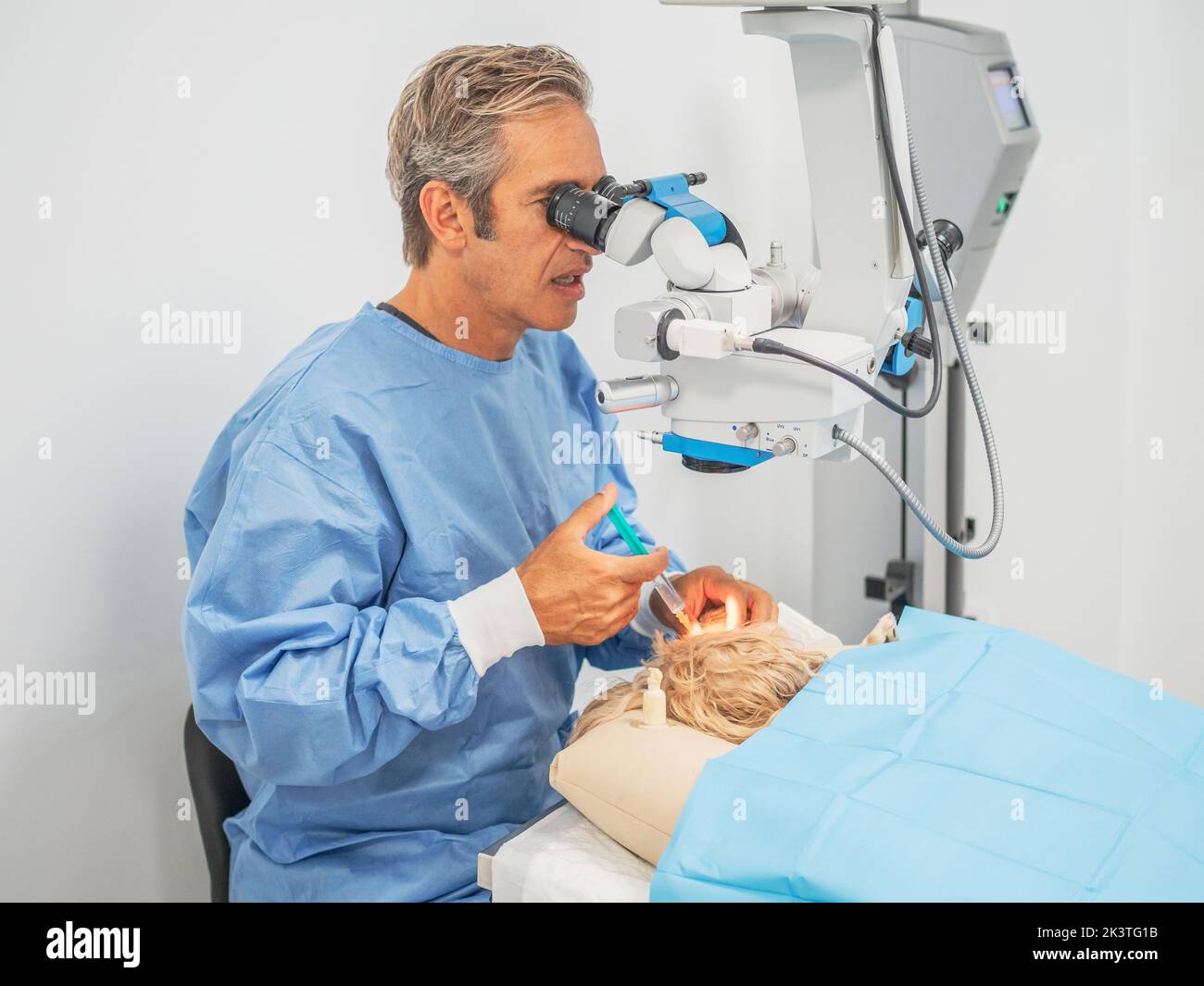 Animal surgeon using operating microscope while injecting medicine into ...