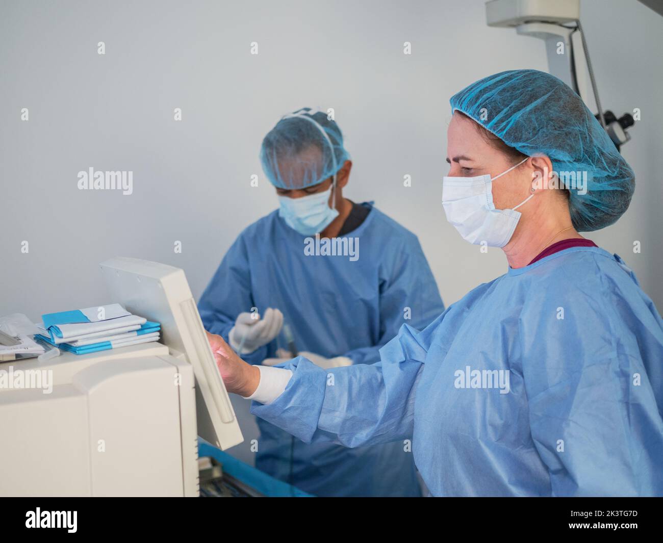 Side view of adult woman in medical uniform operating modern equipment ...