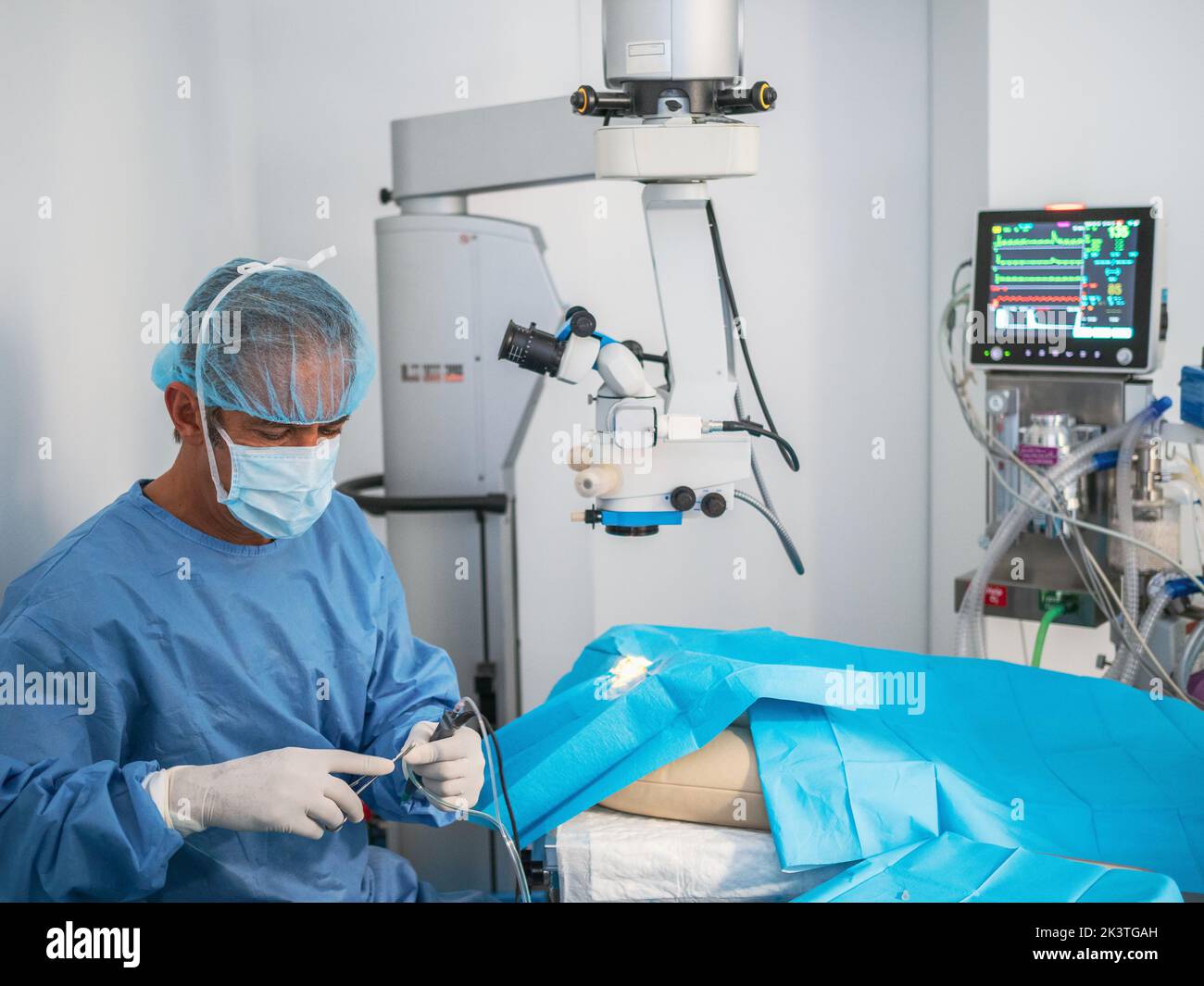 Mature doctor in mask and uniform preparing surgery tools while working ...