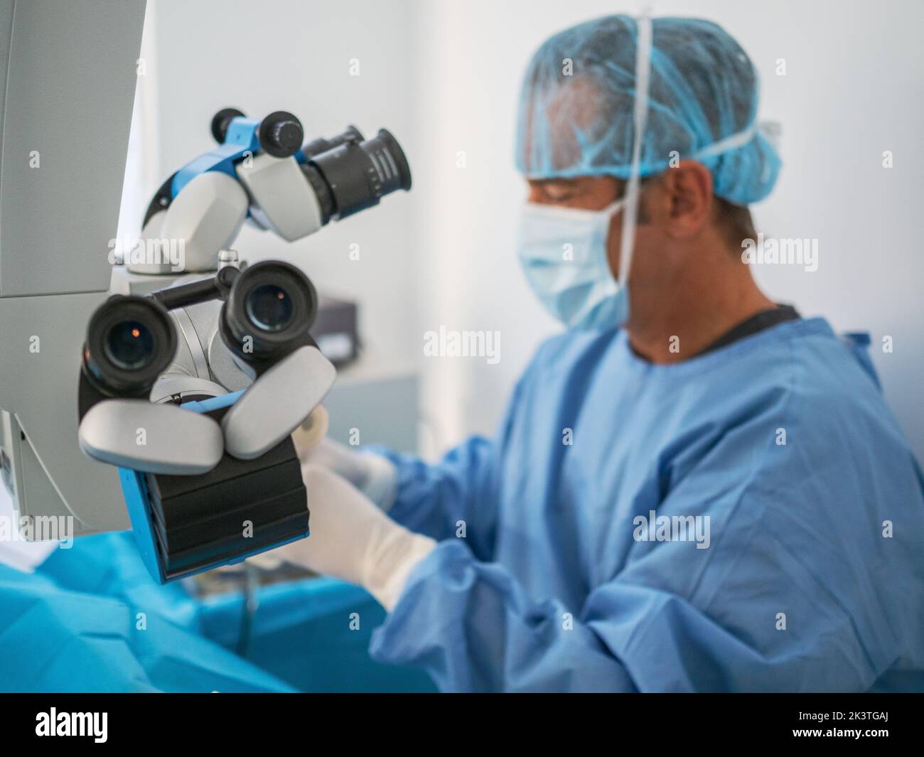 Mature doctor in mask and uniform preparing surgery tools while working ...