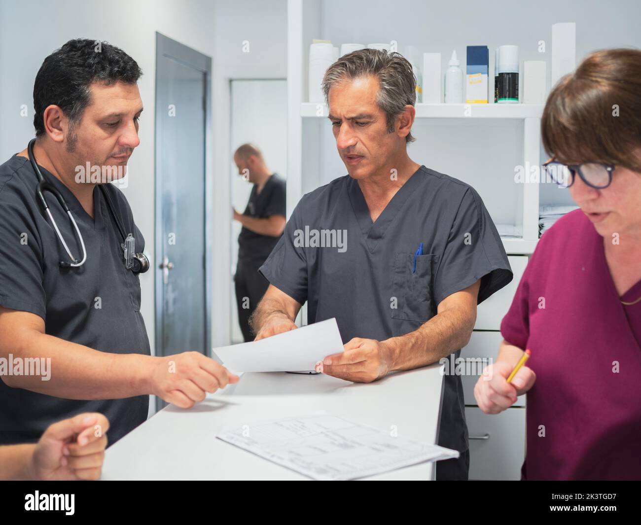 Group of medical practitioners filling and reading documents near ...