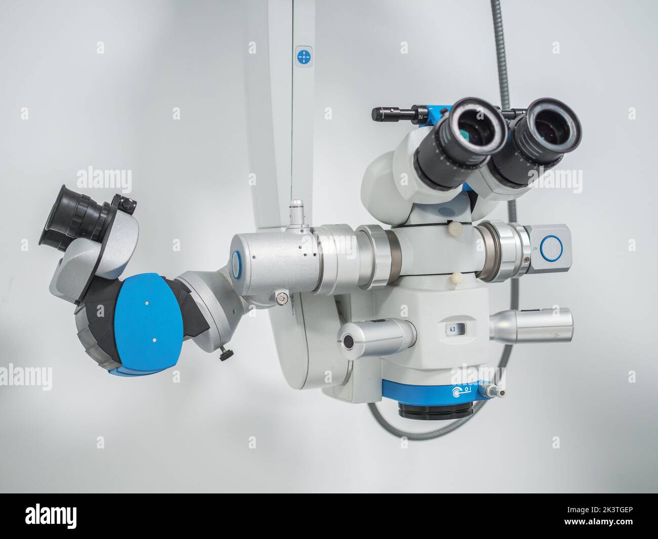 Contemporary operating microscope hanging near white wall against white ...