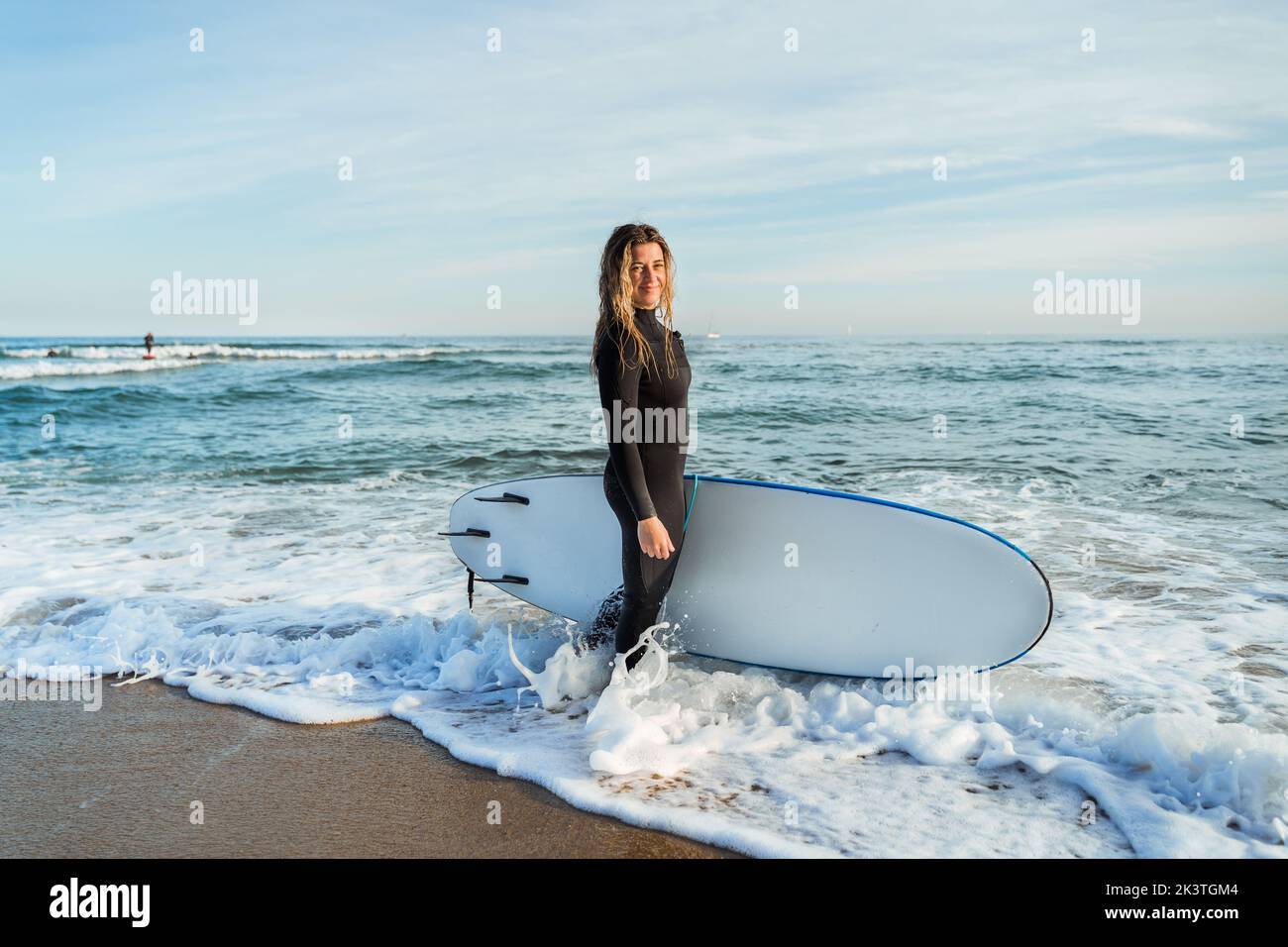 Side view full length of unrecognizable female surfer in wetsuit ...