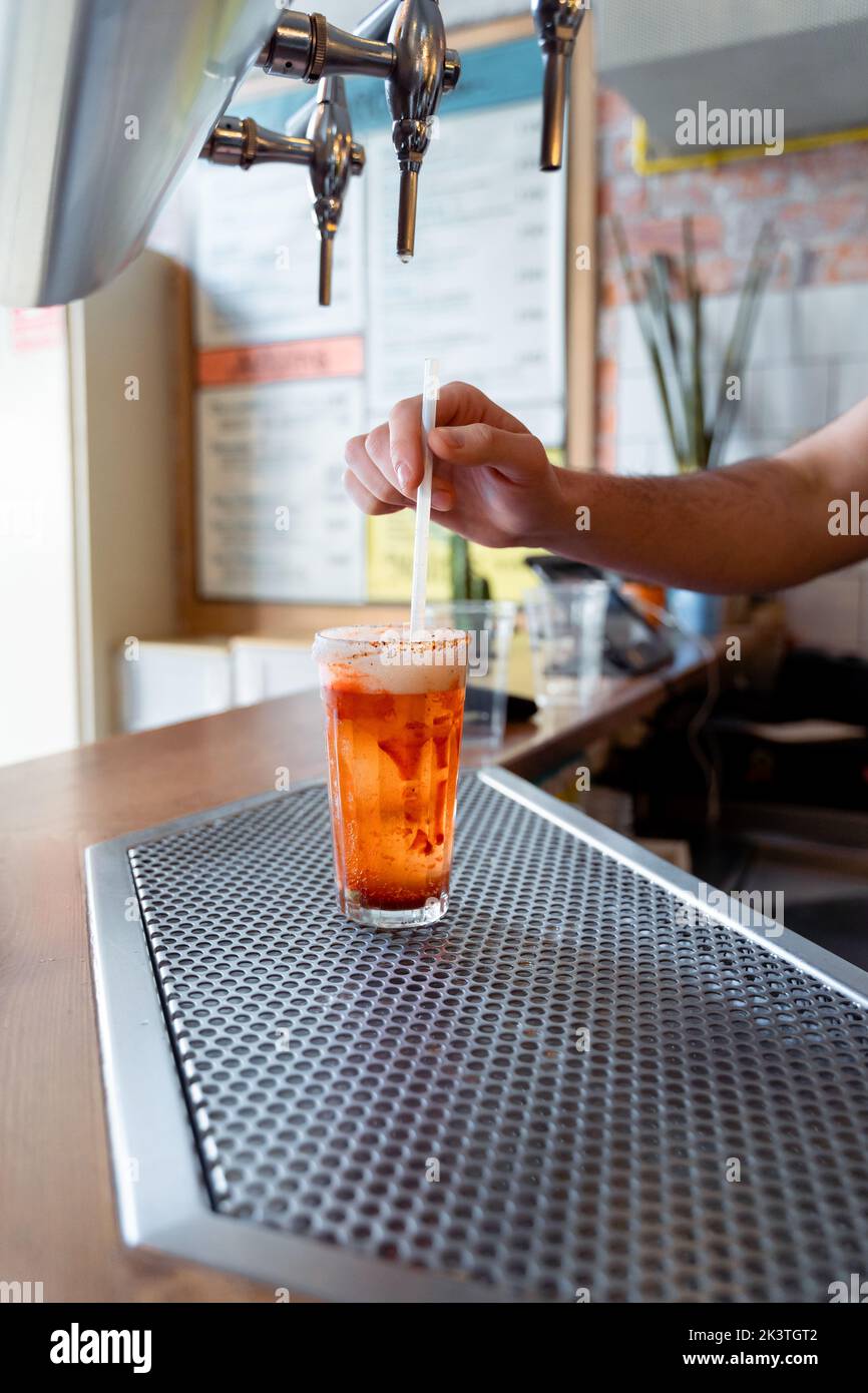 Crop anonymous professional barman stirring delicious cocktail placed ...