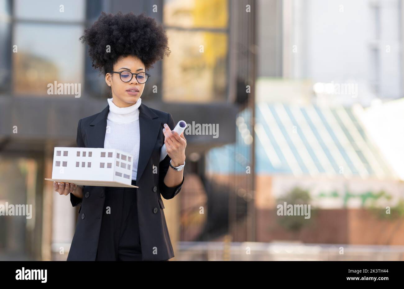 Serious African American female architect standing miniature model and ...