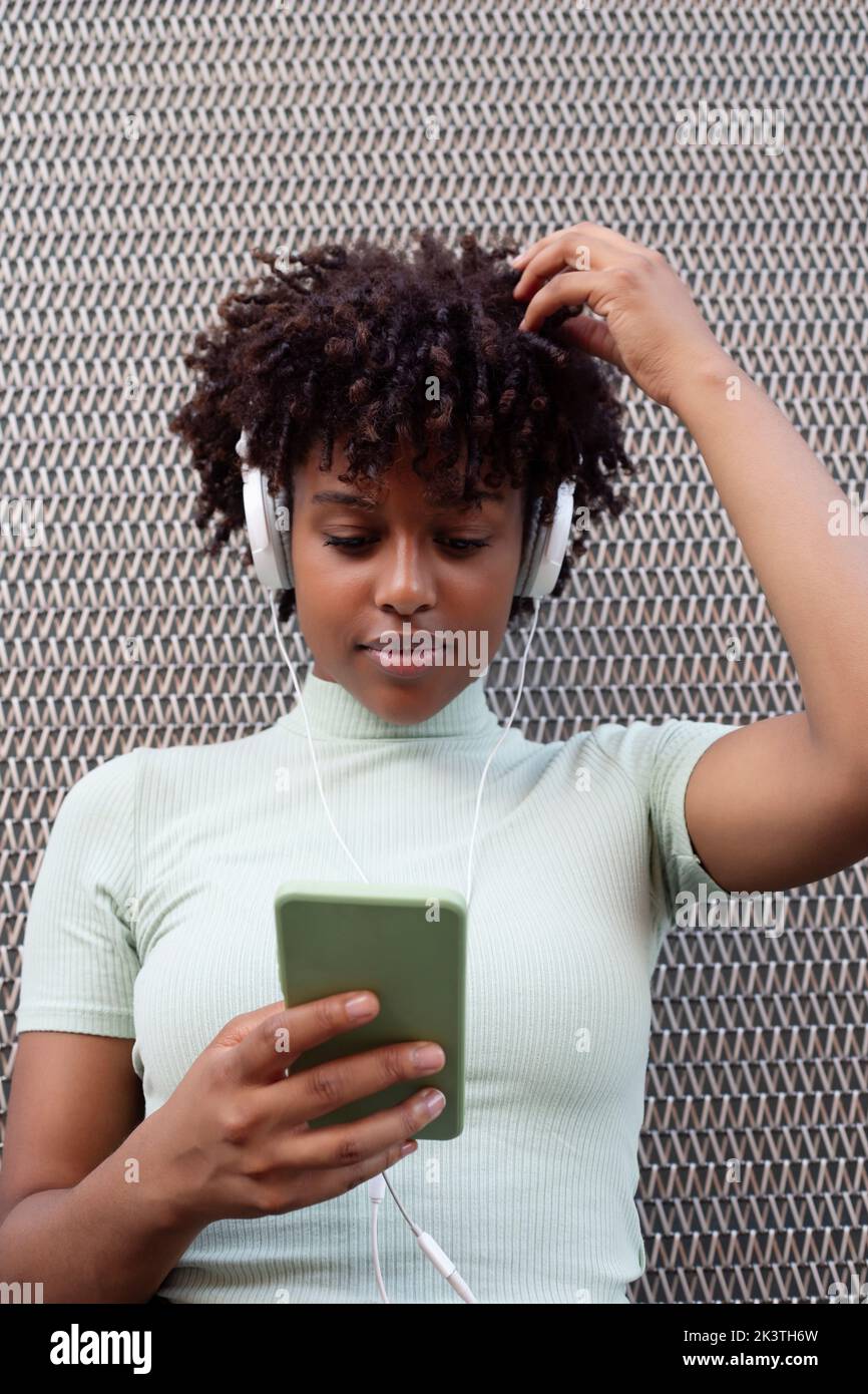 Beautiful young woman with afro hair and headphones listening to music ...