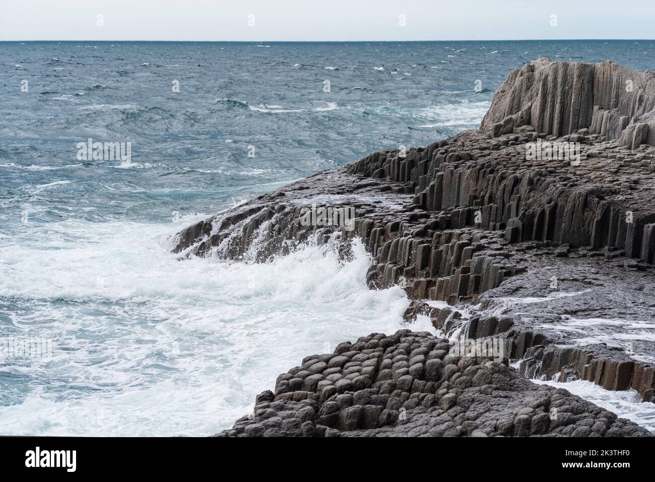 rocky seashore formed by columnar basalt against the backdrop of a ...
