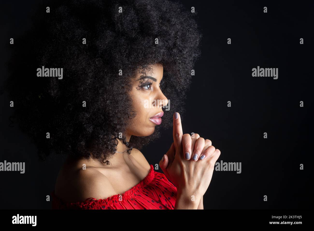 Side view of young Cuban female with Afro hairstyle showing gun gesture ...