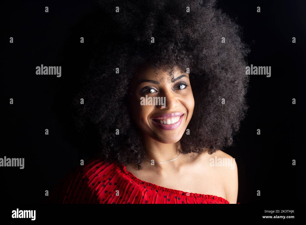 Cheerful young ethnic female with afro hair in ornamental red apparel ...