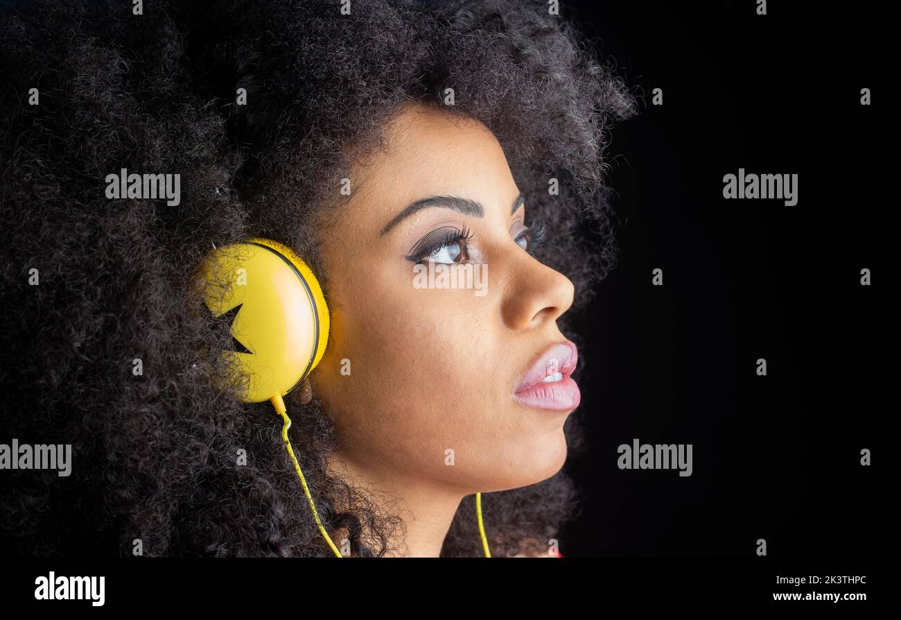 Side view of young Cuban female with makeup in headset listening to ...