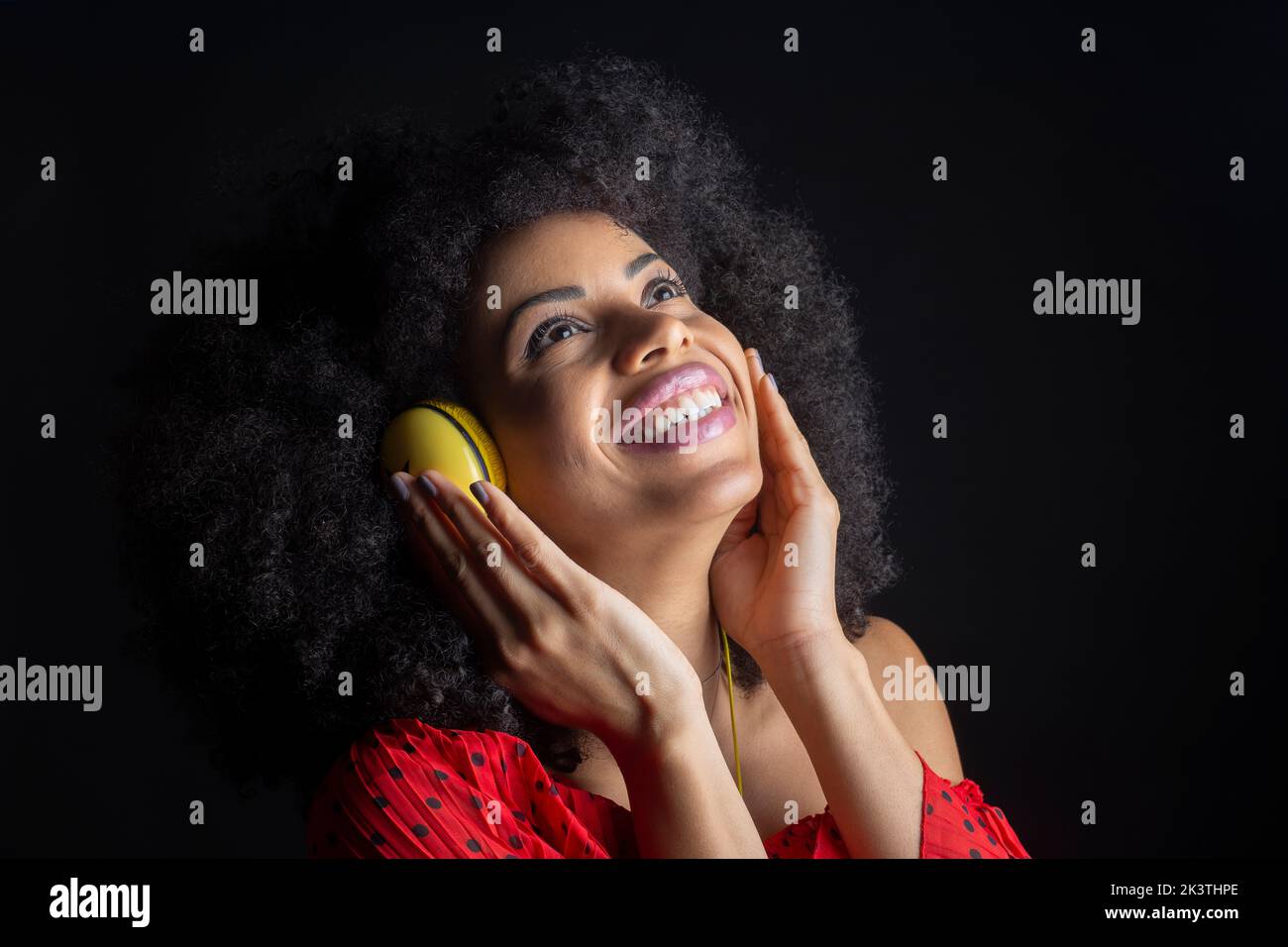 Side view of young delighted Cuban female with makeup in headset ...