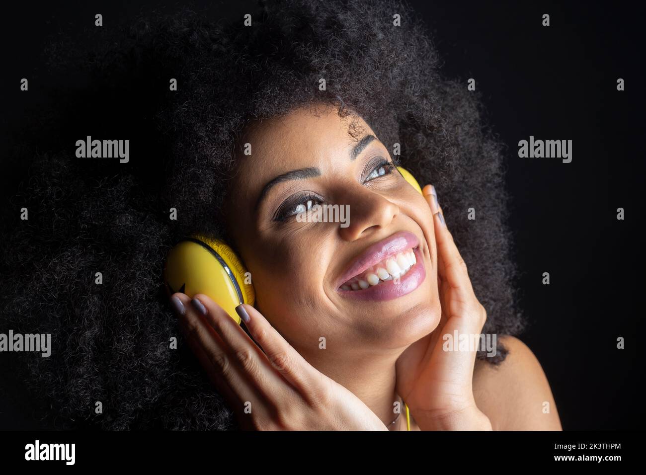 Side view of young delighted Cuban female with makeup in headset ...