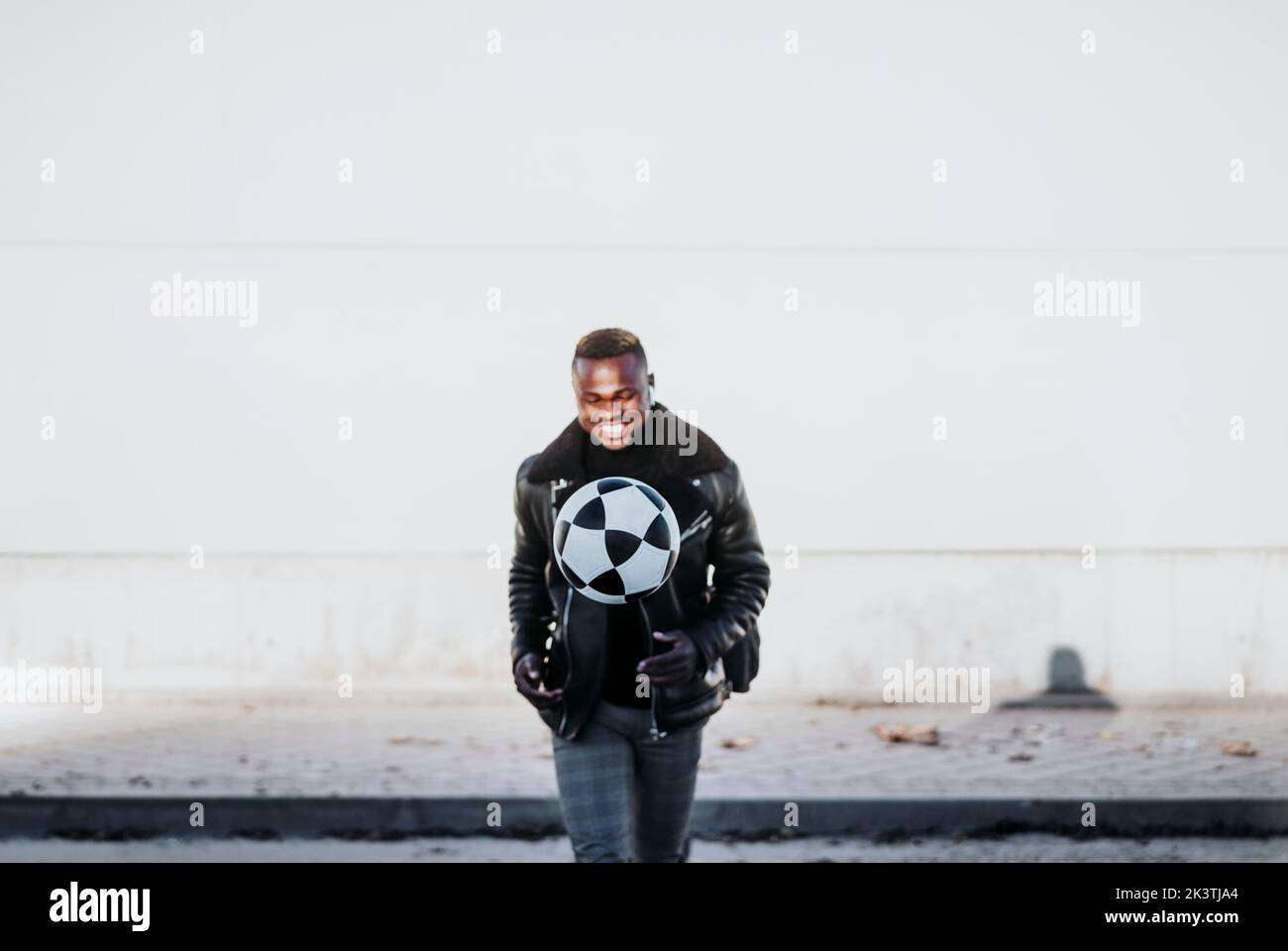 Black man kicking ball on street Stock Photo - Alamy