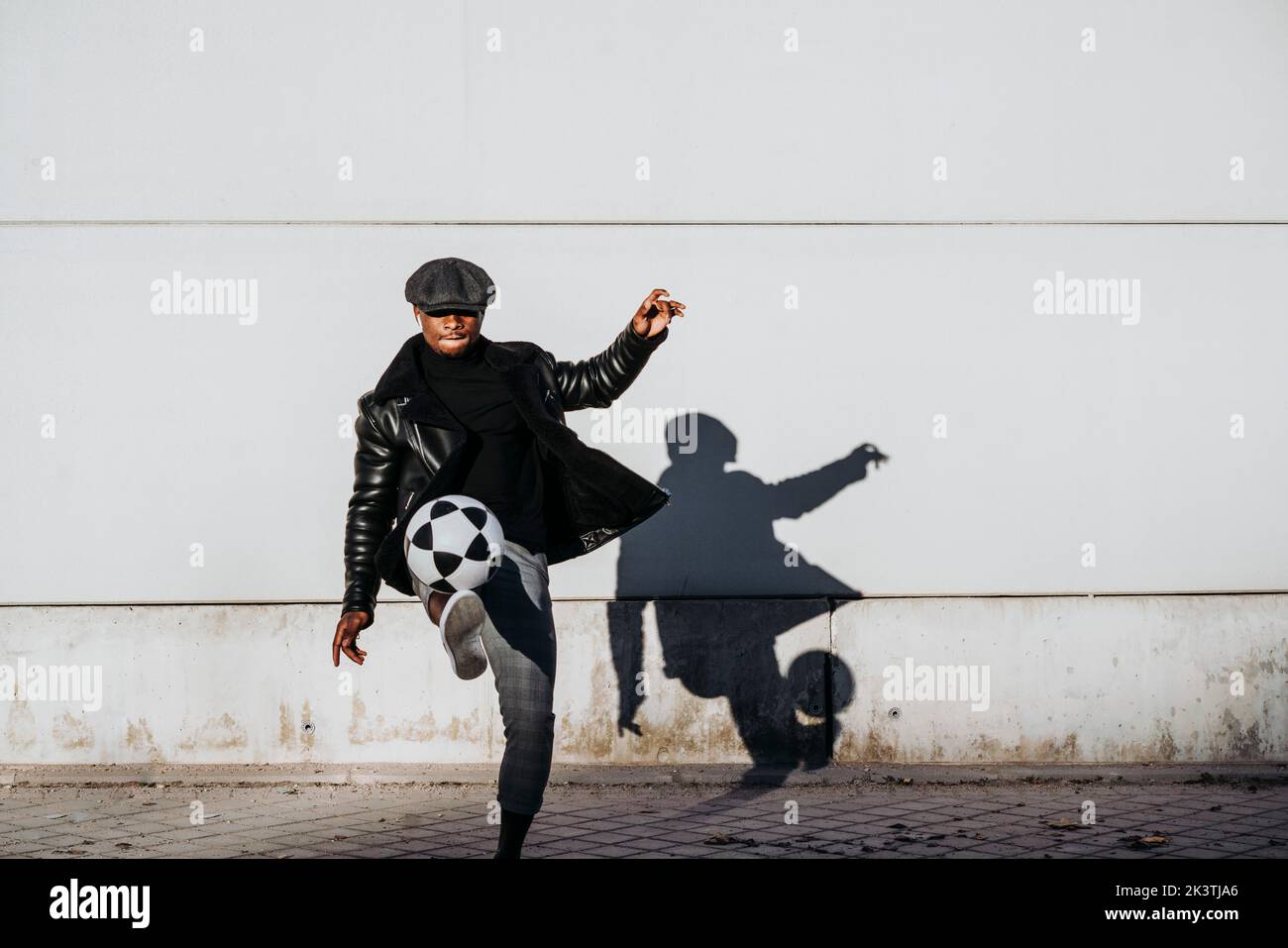 Black man kicking ball on street Stock Photo - Alamy