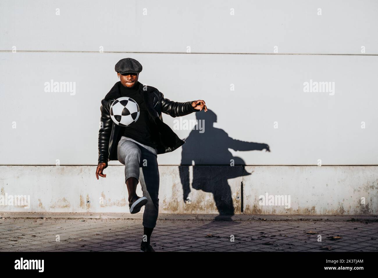 Black man kicking ball on street Stock Photo - Alamy