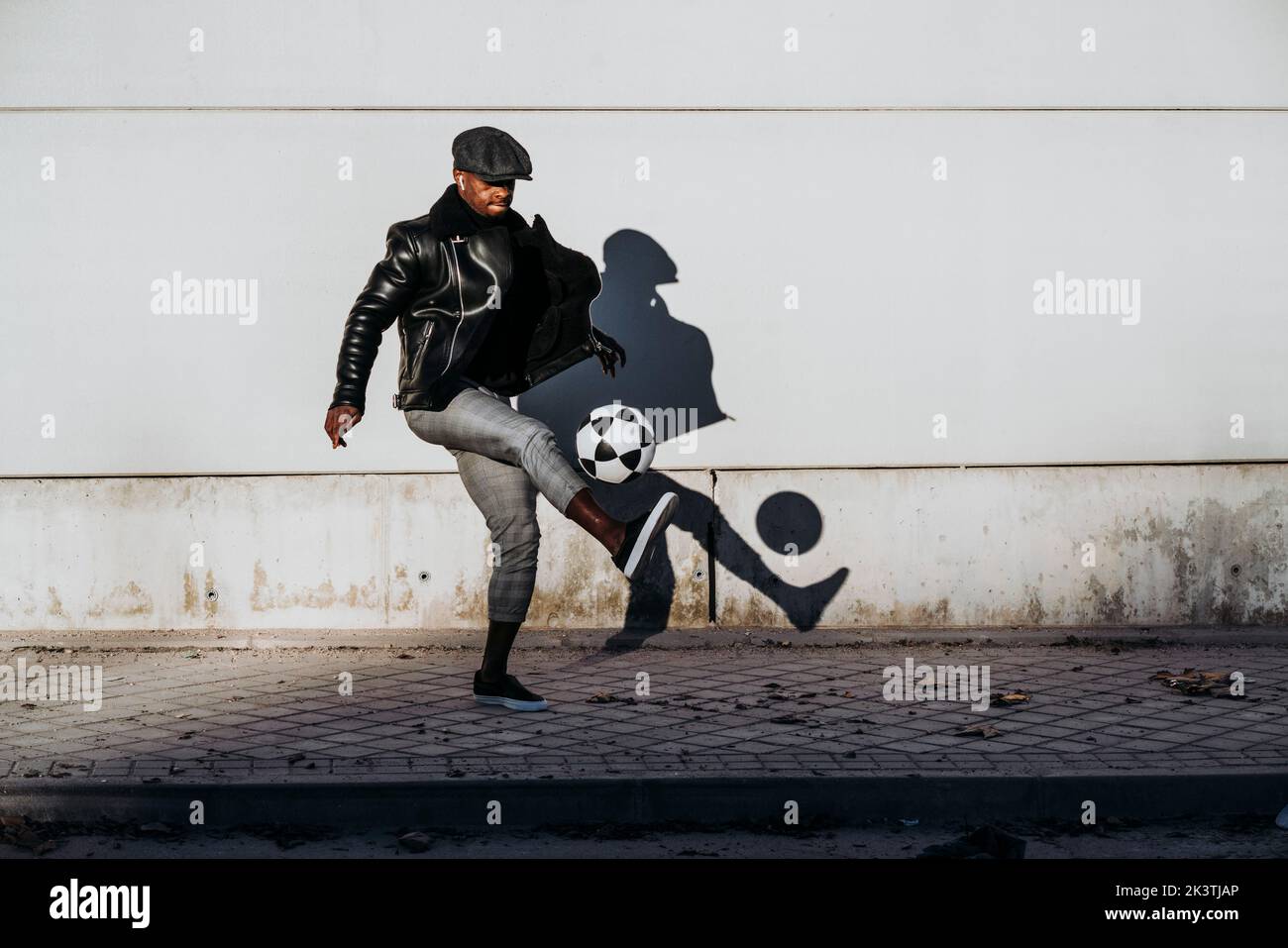Black man kicking ball on street Stock Photo - Alamy