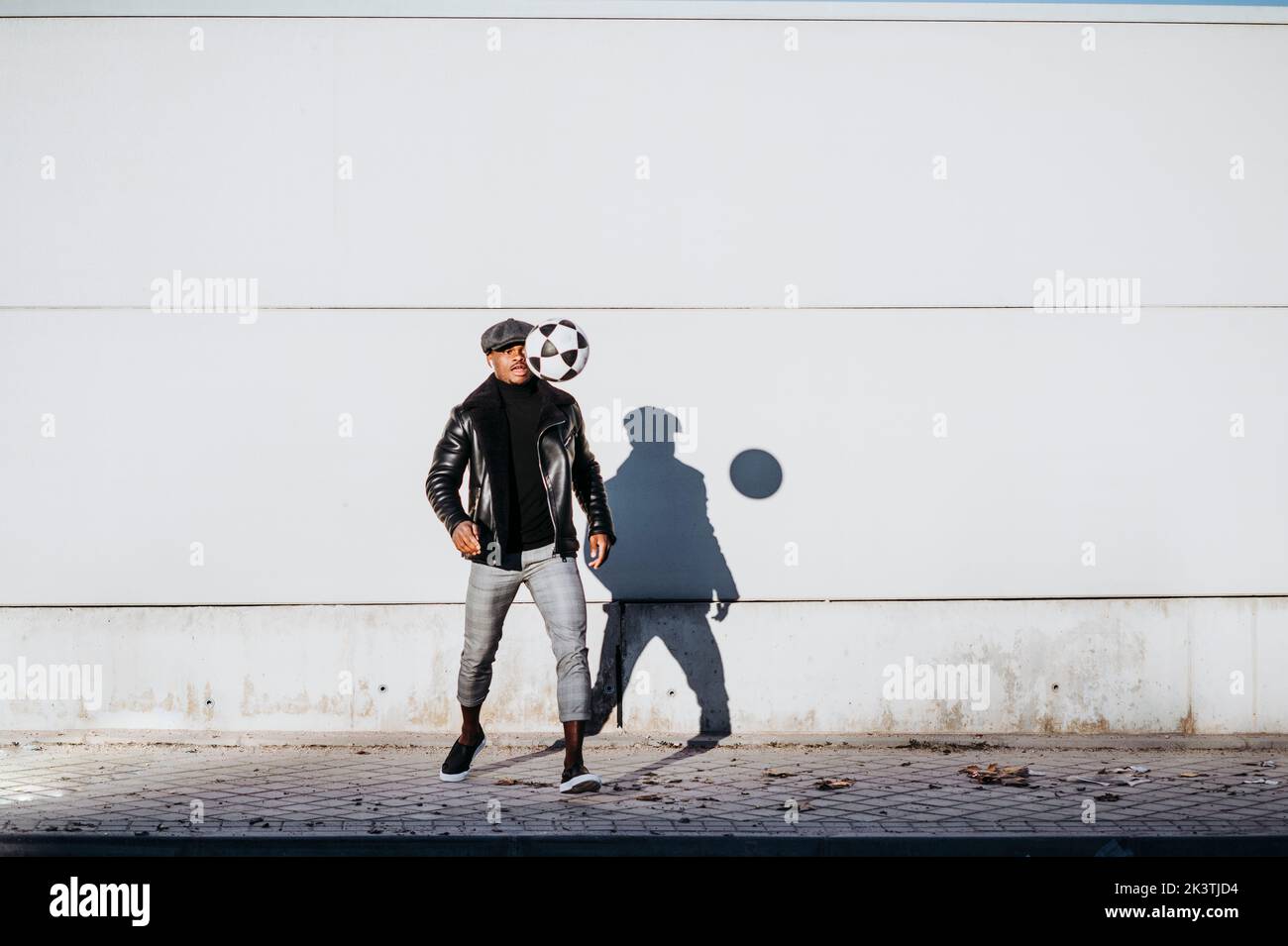 Black man kicking ball on street Stock Photo - Alamy